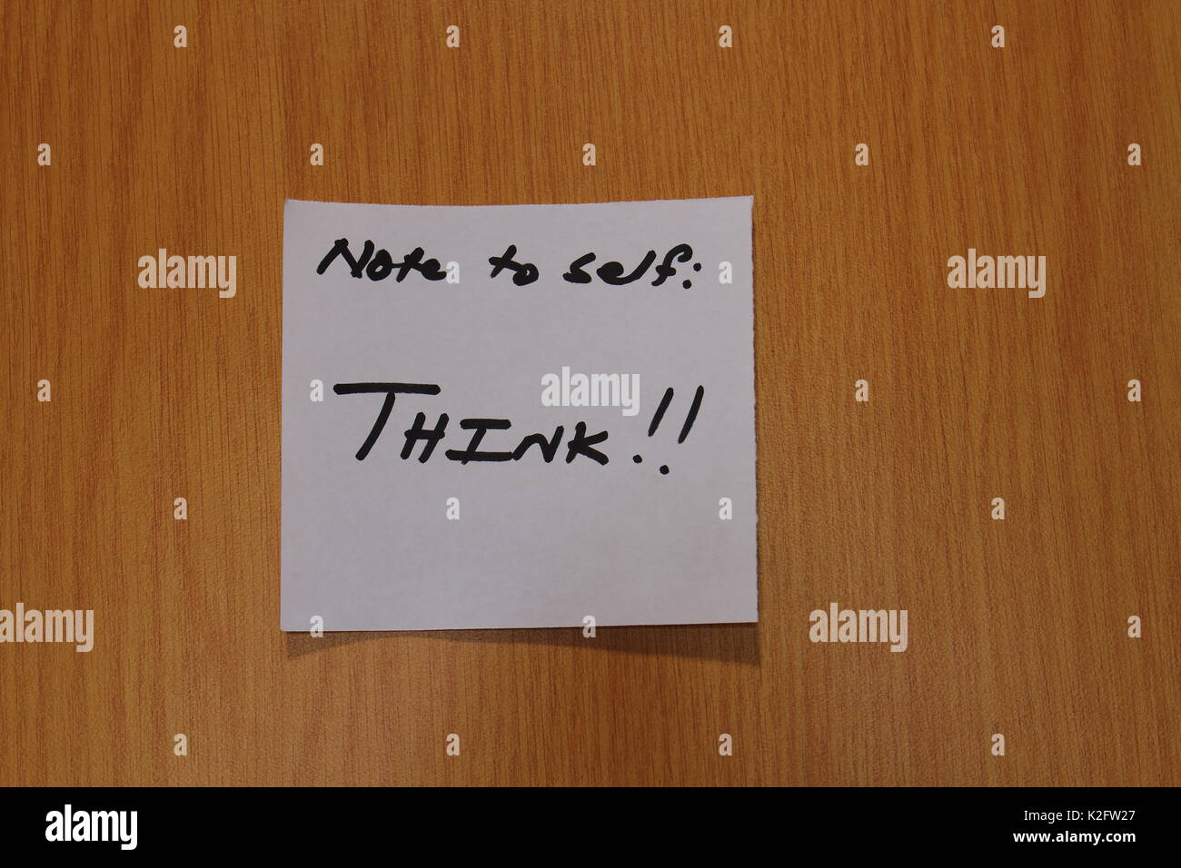 Hand written note with the term Think on it stuck to the wood surface ...