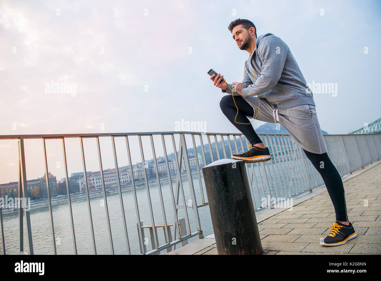 A handsome young man putting his leg up and leaning on it while using ...
