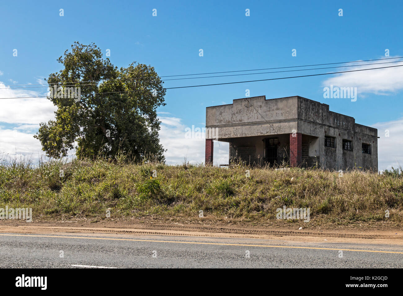 Old abandoned rural roadside store tree and powerlines against blue ...