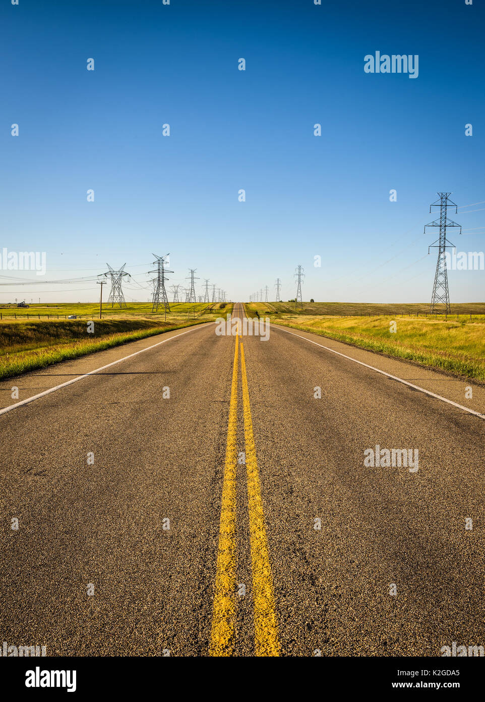 High electricity Pillars with , transmission lines along an empty road ...