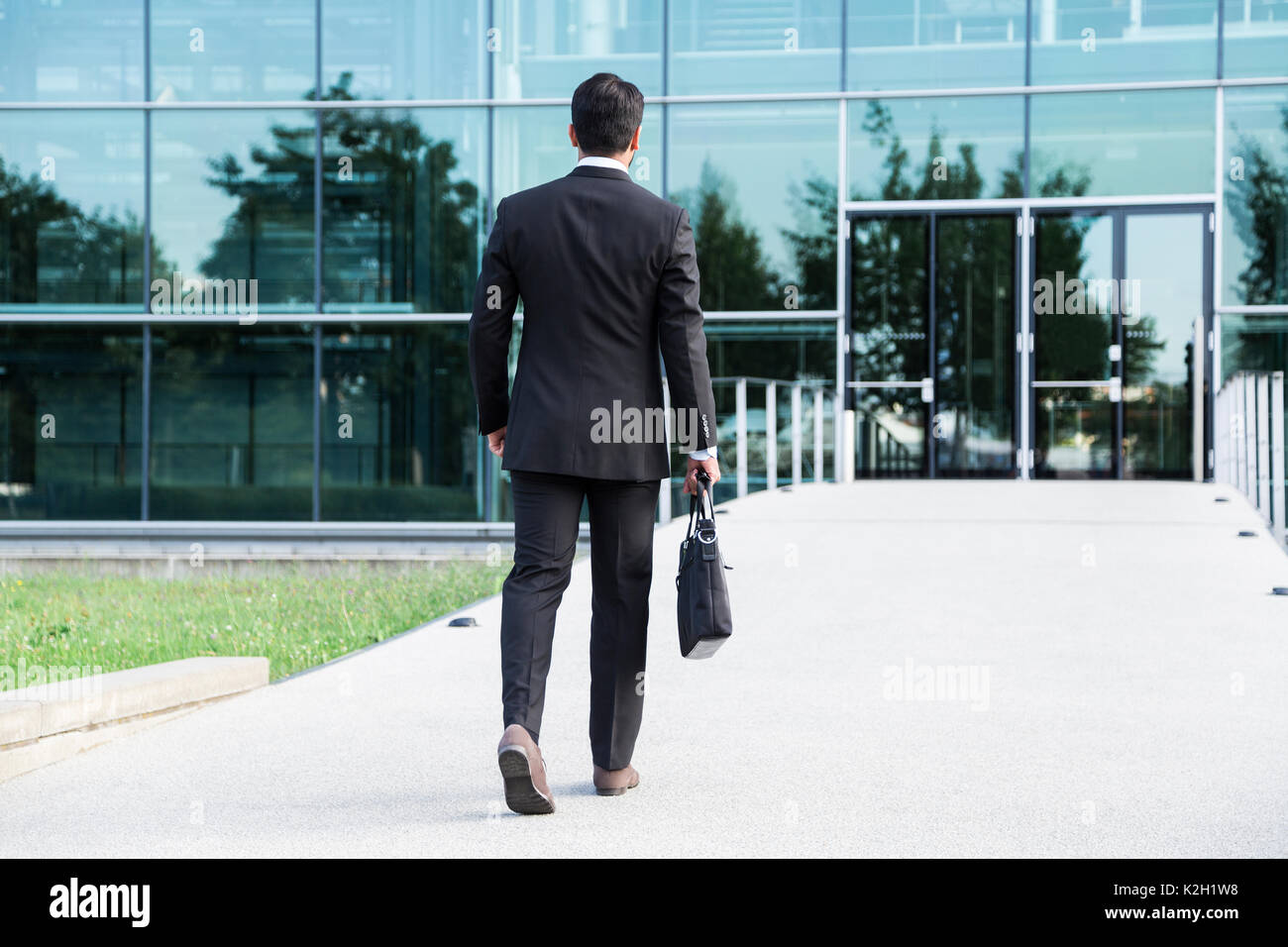 Anonymous businessman or worker in black suit with leather handbag or ...