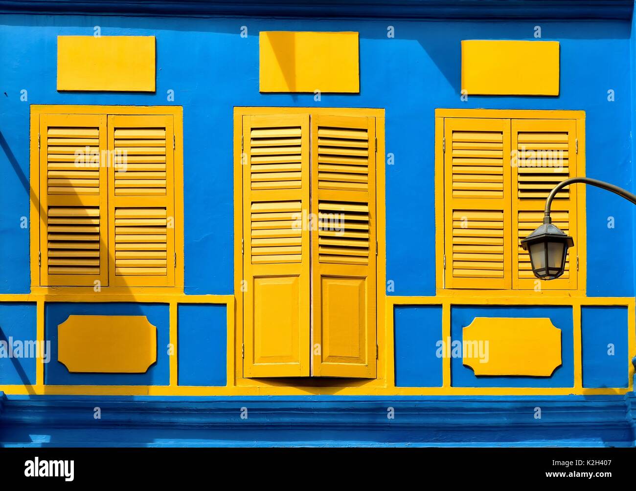 Traditional shop house exterior with yellow wooden louvered shutters ...