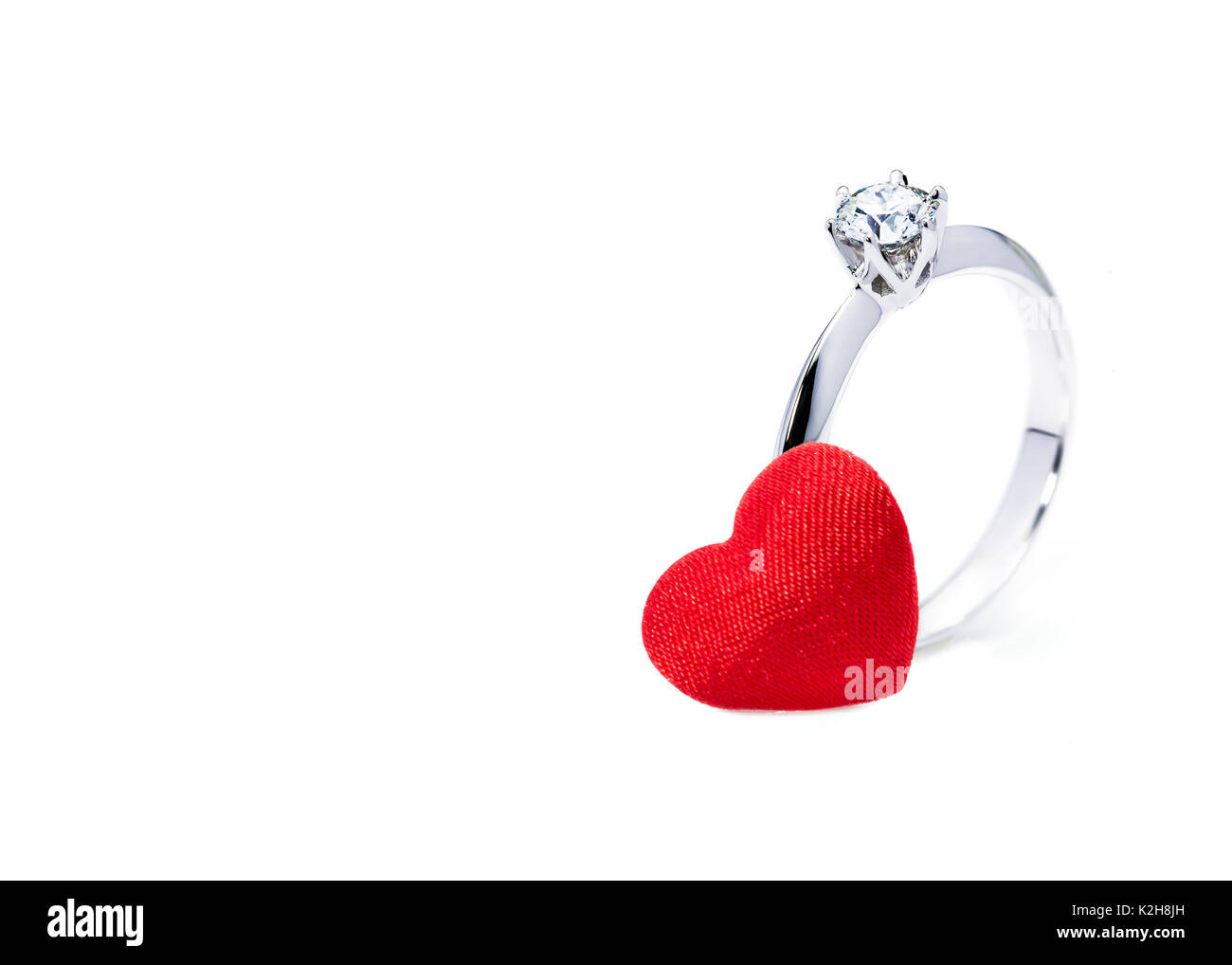 standing up beautiful diamond ring and a red felt heart on white ...