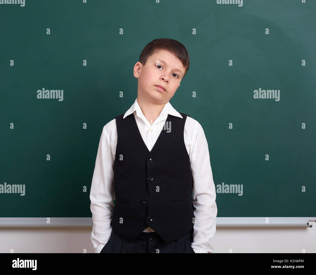 indifferent school boy portrait near green blank chalkboard background ...