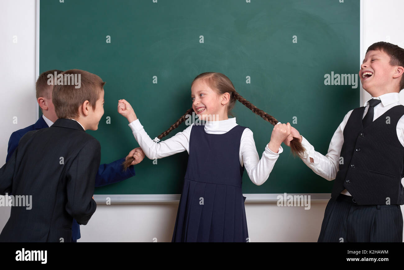 child play and having fun, boys pull the girl braids, near blank school ...