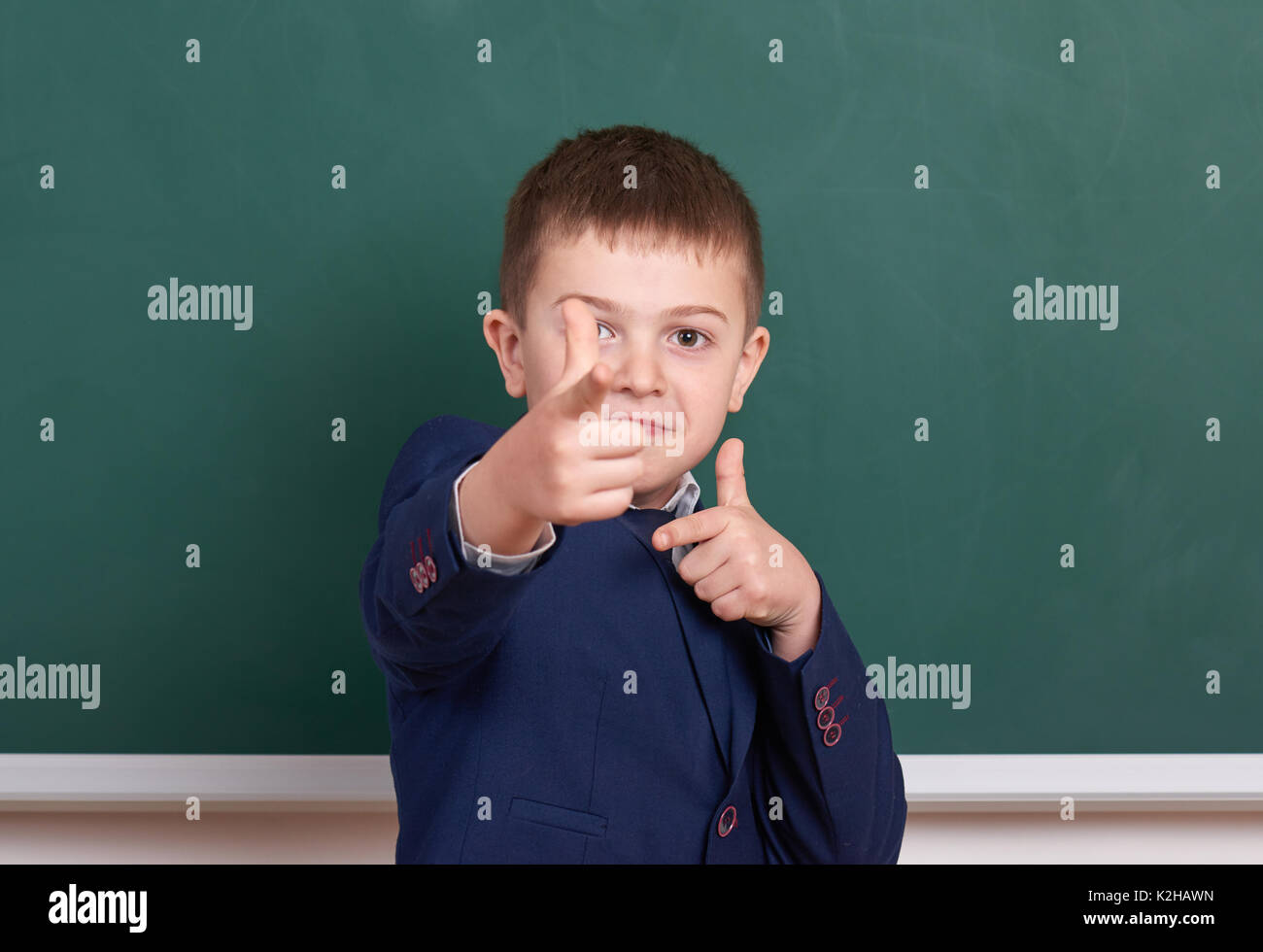 school boy portrait near green blank chalkboard background, point ...