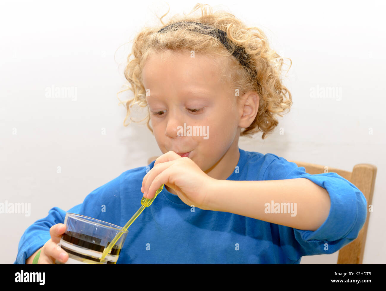 a cute little boy is drinking red juice using straw Stock Photo - Alamy