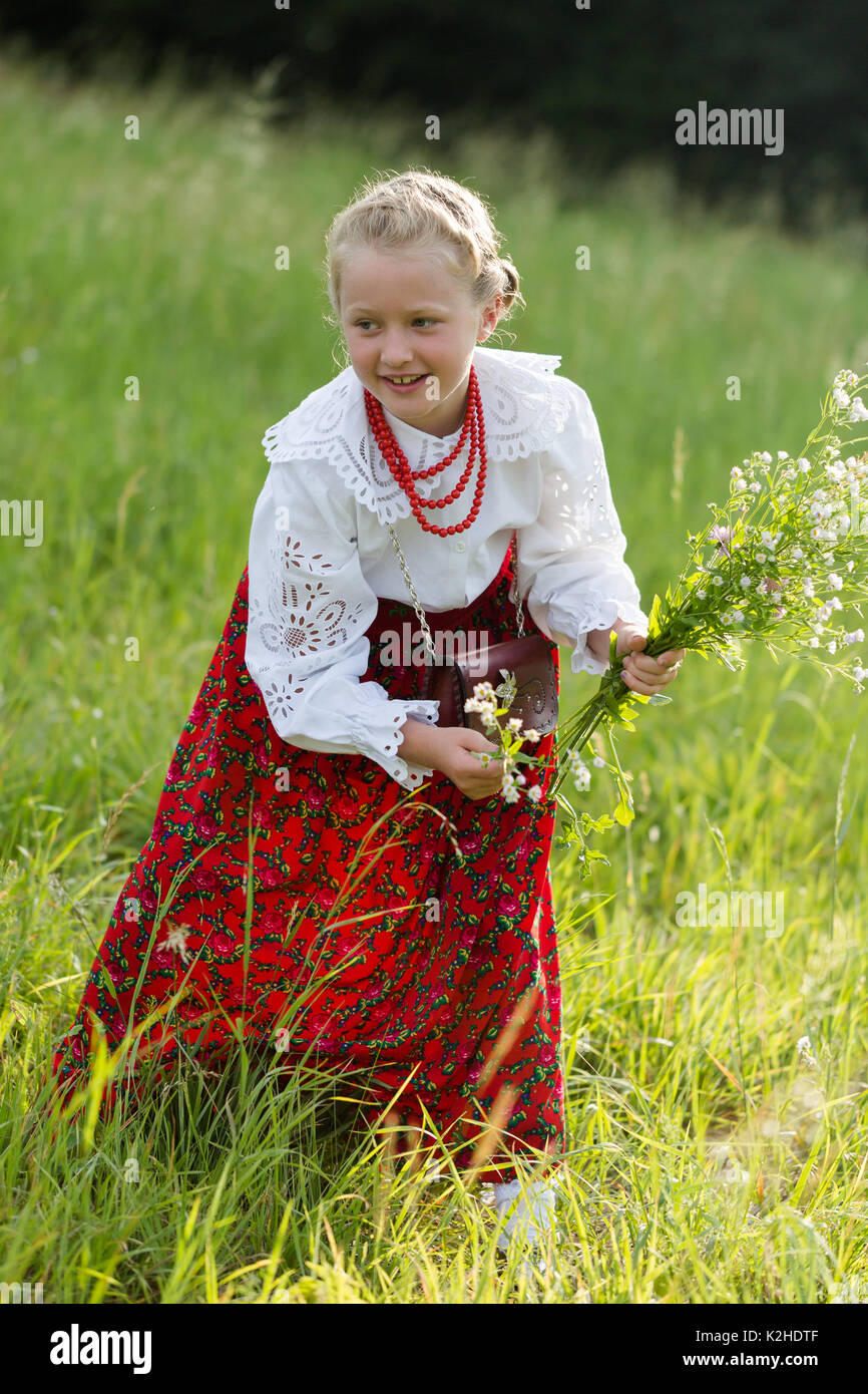 Young smiling girl in traditional Polish mountain people dress picking ...