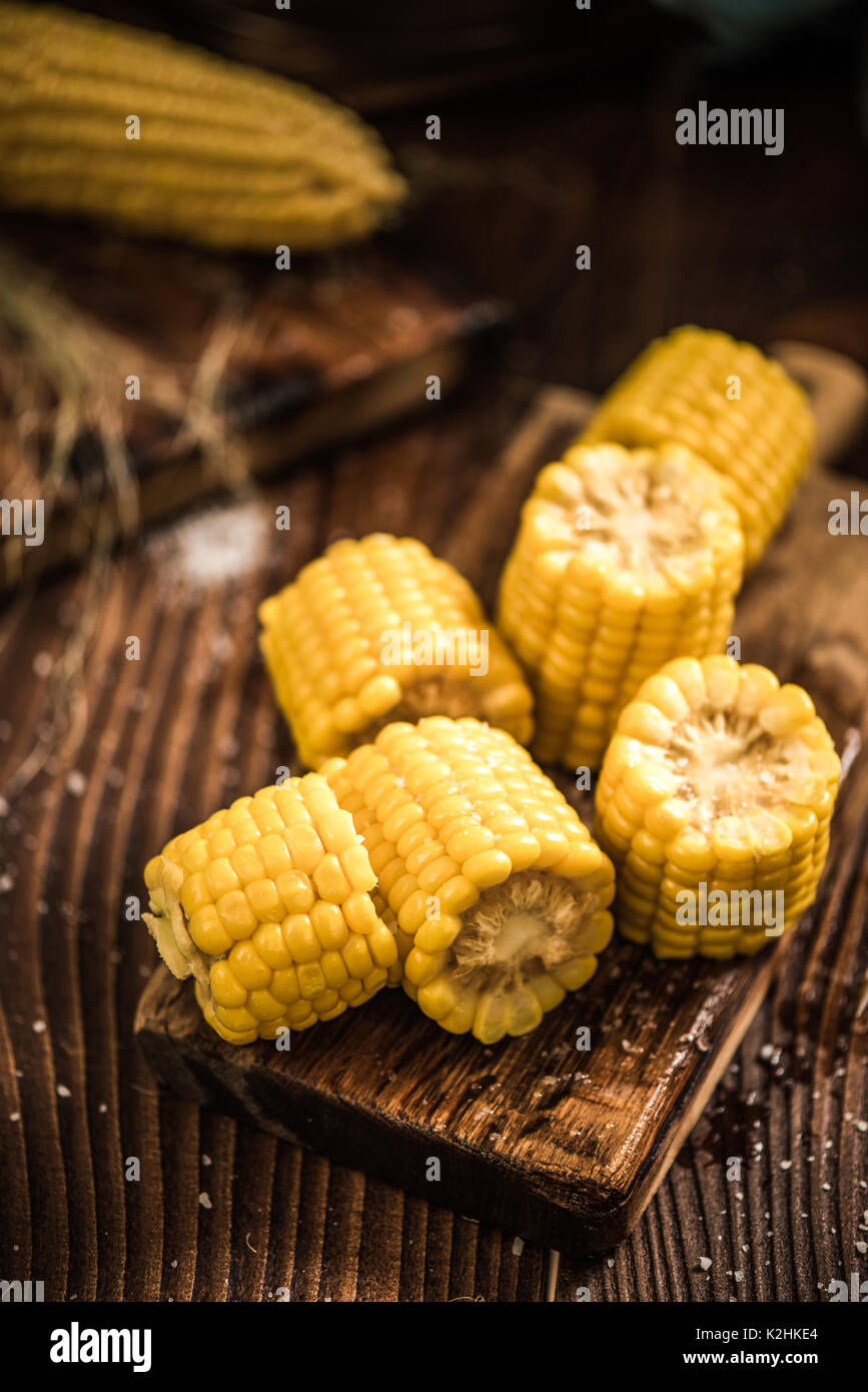 Cooked and salted corn on cob with butter, served on wooden rustic ...