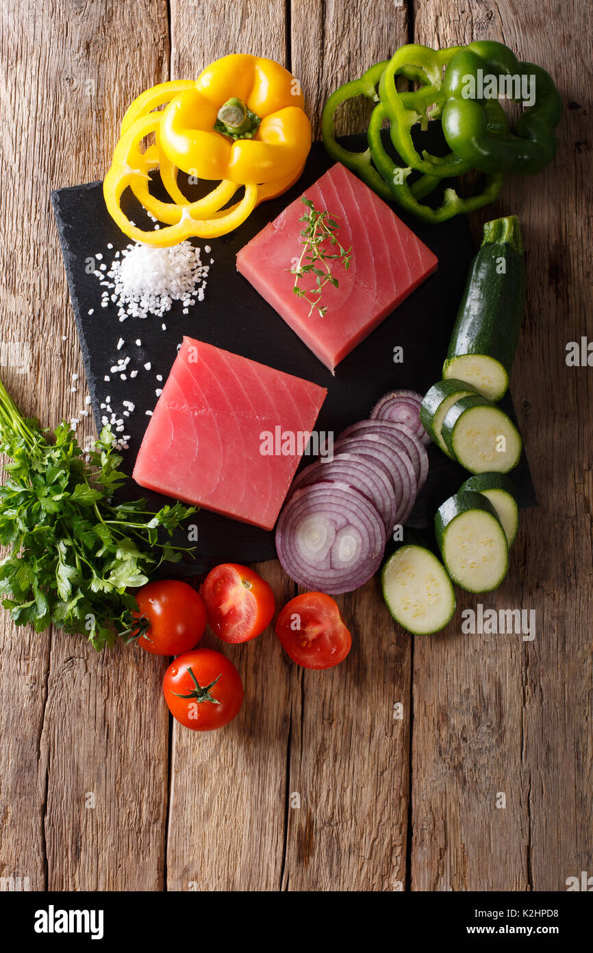 Raw fillet of tuna surrounded by fresh vegetables and spices close-up ...