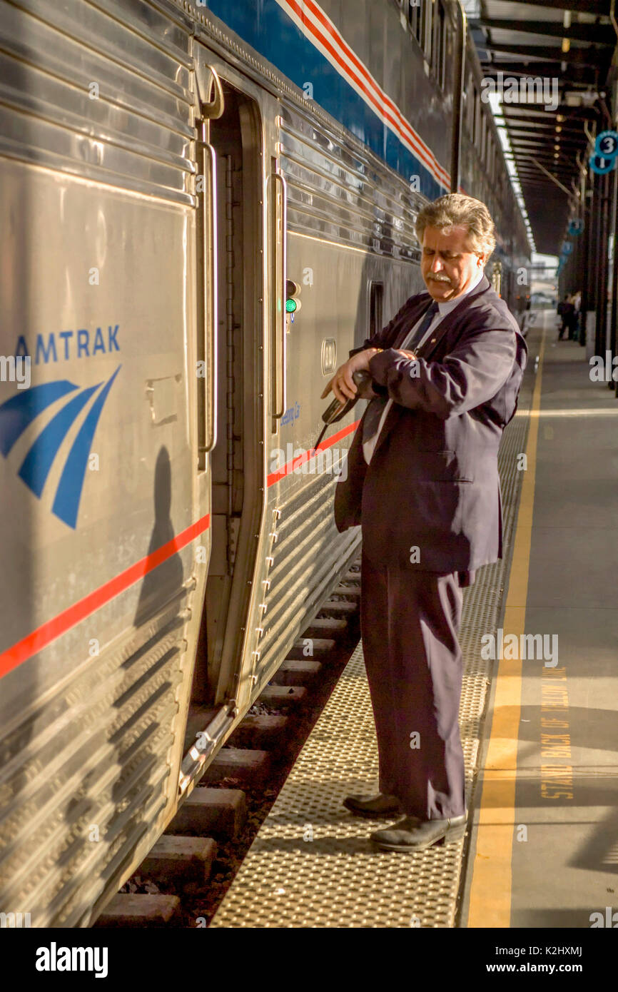 In bright afternoon sunlight, a uniformed middle-aged train conductor ...