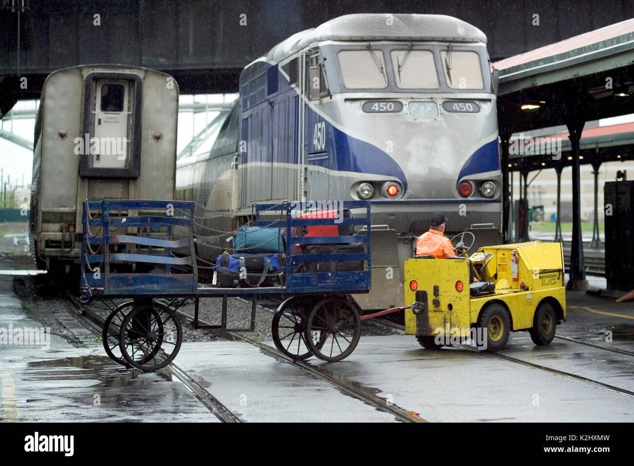 An electric cart pulls a cart of arriving passenger's baggage past a ...