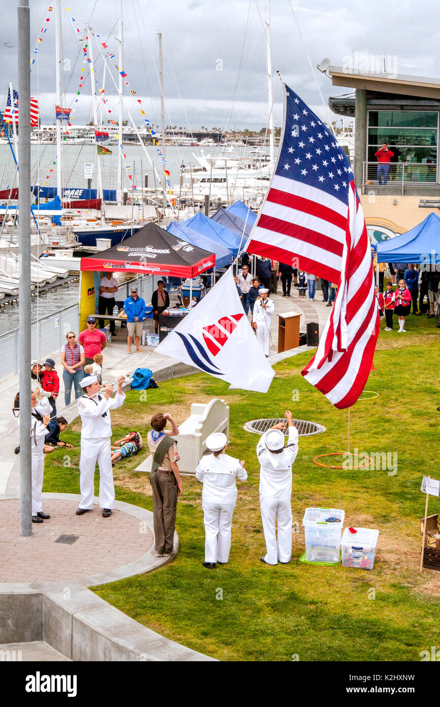 Multiracial Boy Scouts and Sea Scouts raise a billowing US flag as ...