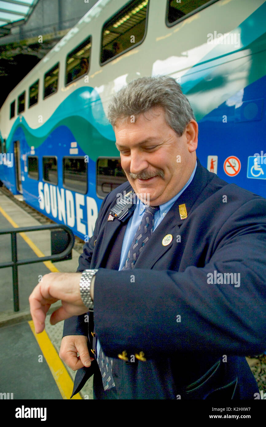 A railroad conductor in King Street Station in Seattle, WA, checks his ...