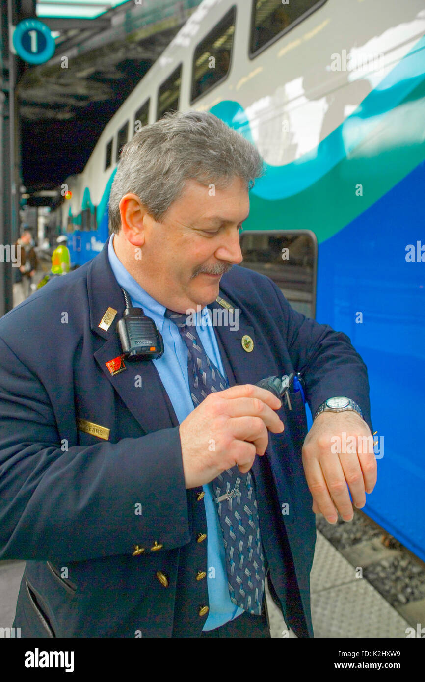 A railroad conductor in King Street Station in Seattle, WA, checks his ...