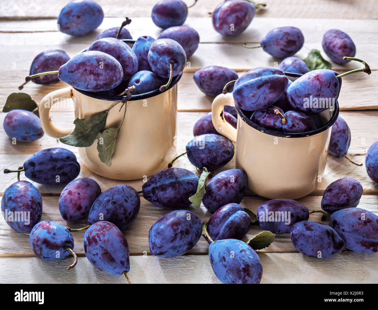 Plums of blue juicy sweet lie in tin-plated metal mugs of yellow color ...