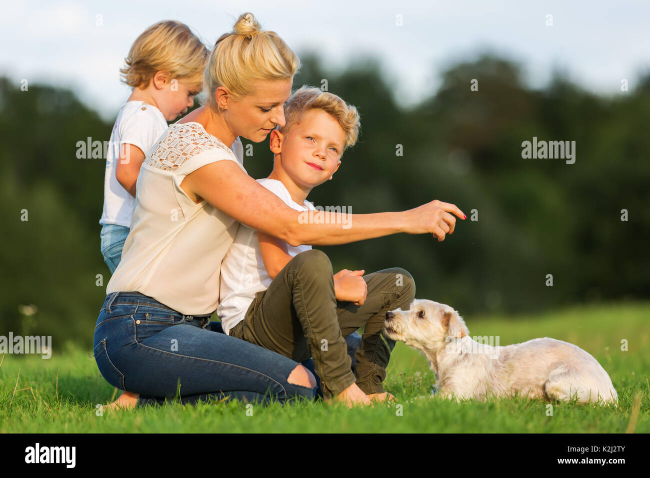 picture of a mother with two children they play with a small dog ...