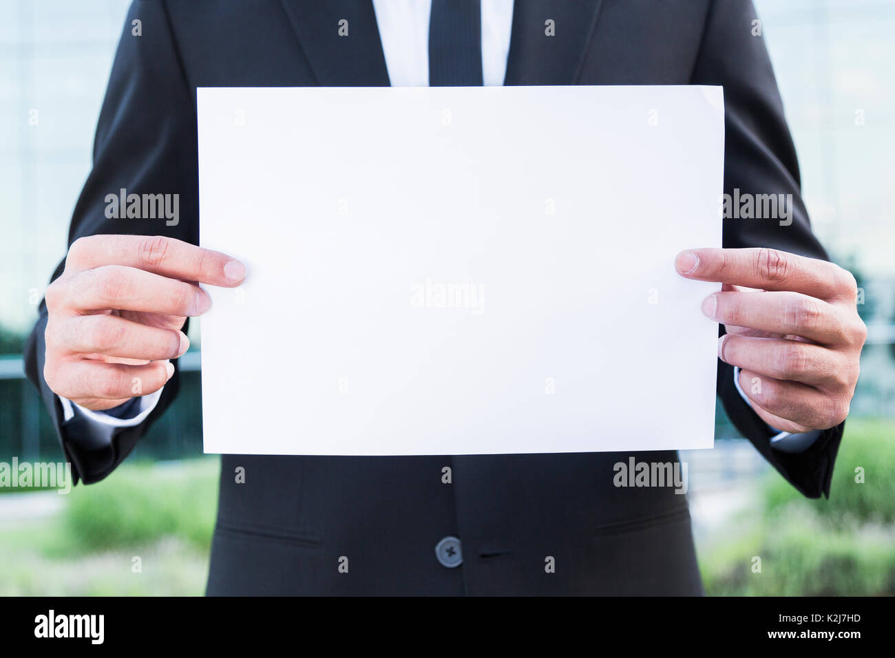 Anonymous businessman or worker in black suit with tie and shirt holds ...