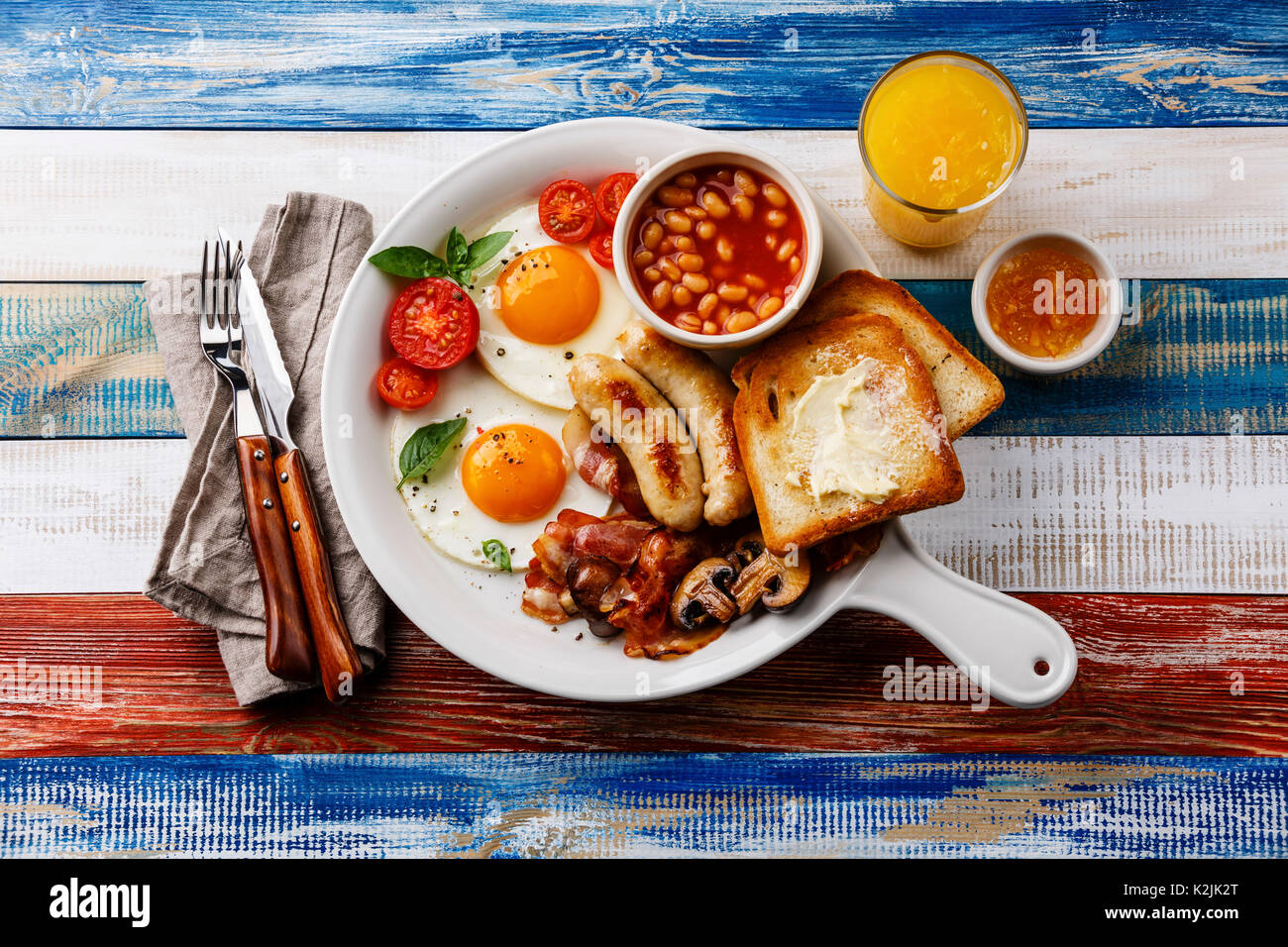 English breakfast in white pan with fried eggs, sausages, bacon, beans ...