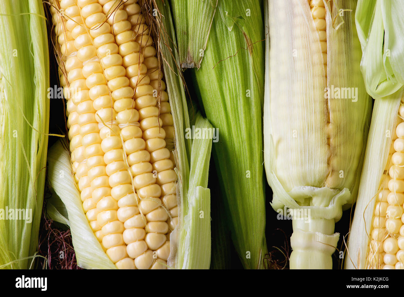 Young raw uncooked corn cobs in leaves. Close up, top view. Food ...