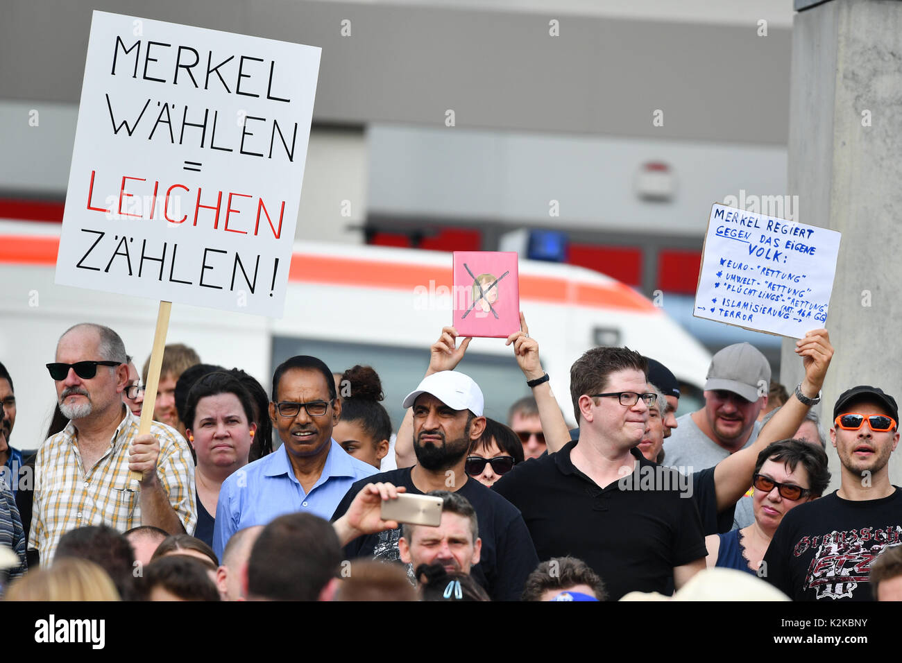 A man holding a sign with the inscription "voting for Merkel = counting ...
