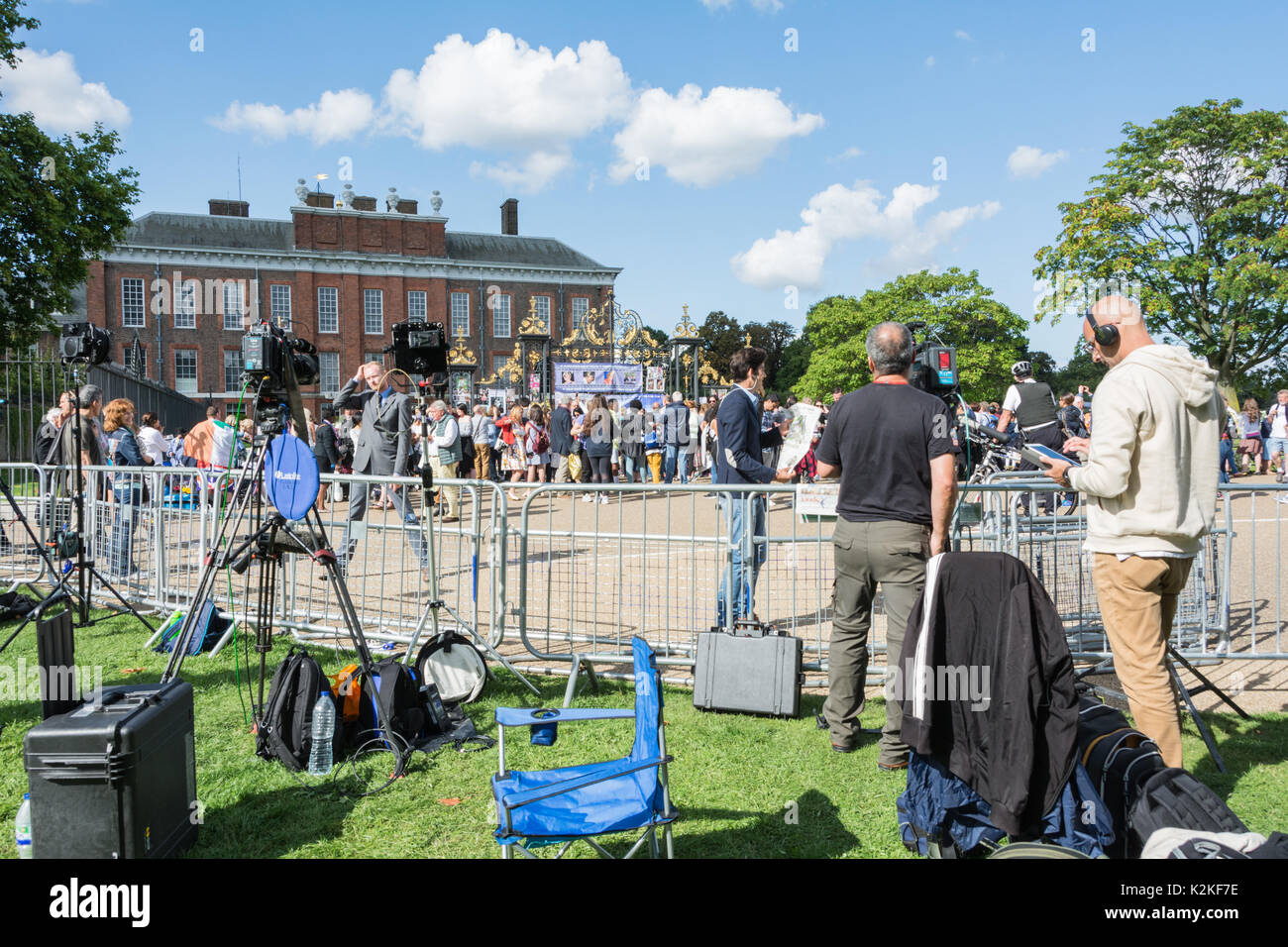 A news reporter and cameraman with a piece to camera outside the gates ...