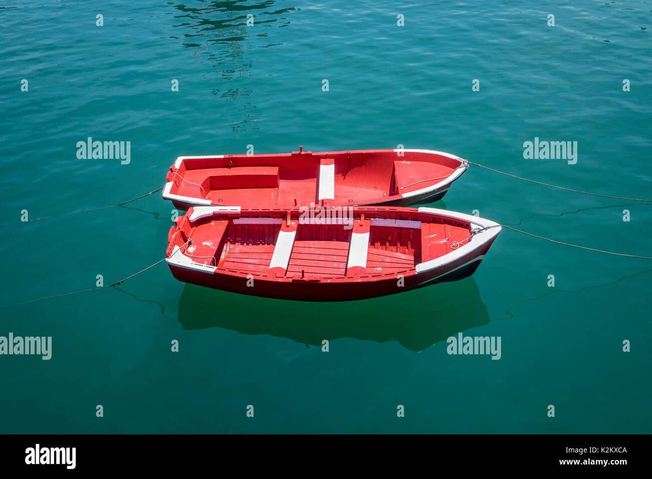 Two red rowing boats anchored on a green sea Stock Photo - Alamy