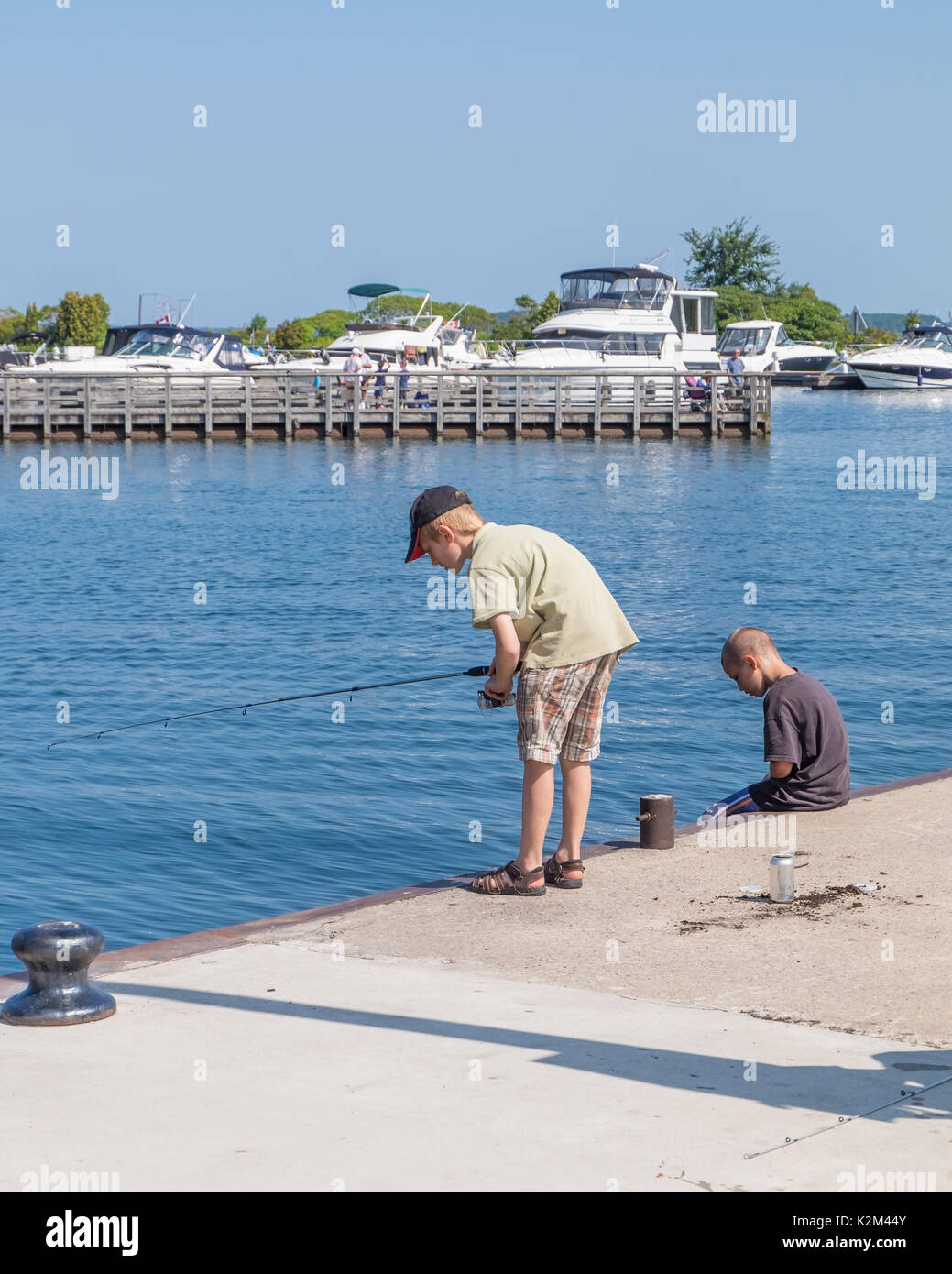 Young boys busy fishing off the pier at the waterfront in Orillia ...