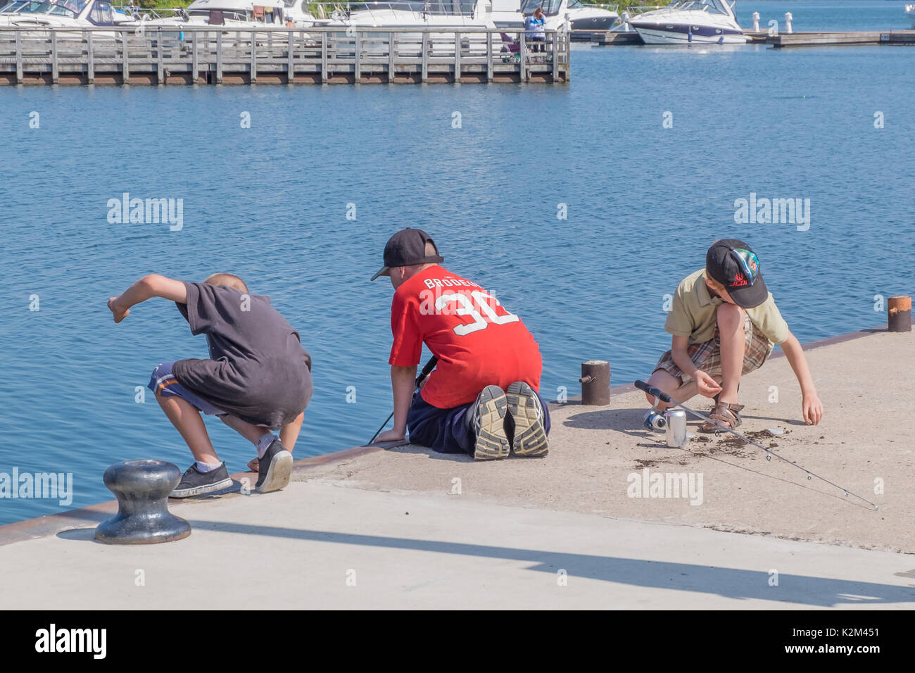Three young boys fishing off a pier at the waterfront in Orillia ...