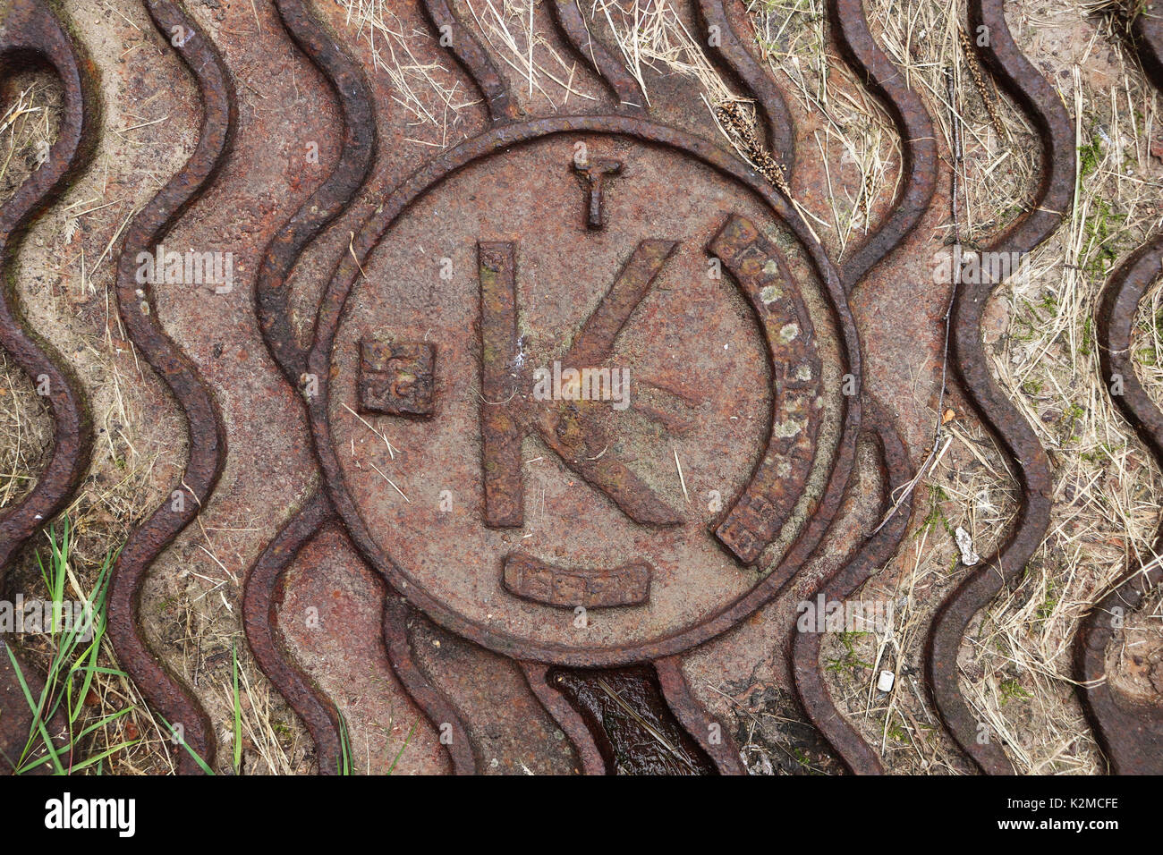 Rust metal hatchwaywith big K letter and wave ornament. Urban city ...