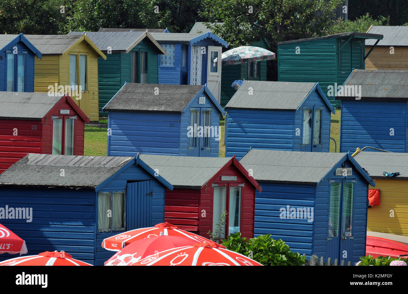 Brightly coloured beach huts on the seashore in a coastal scene on the ...