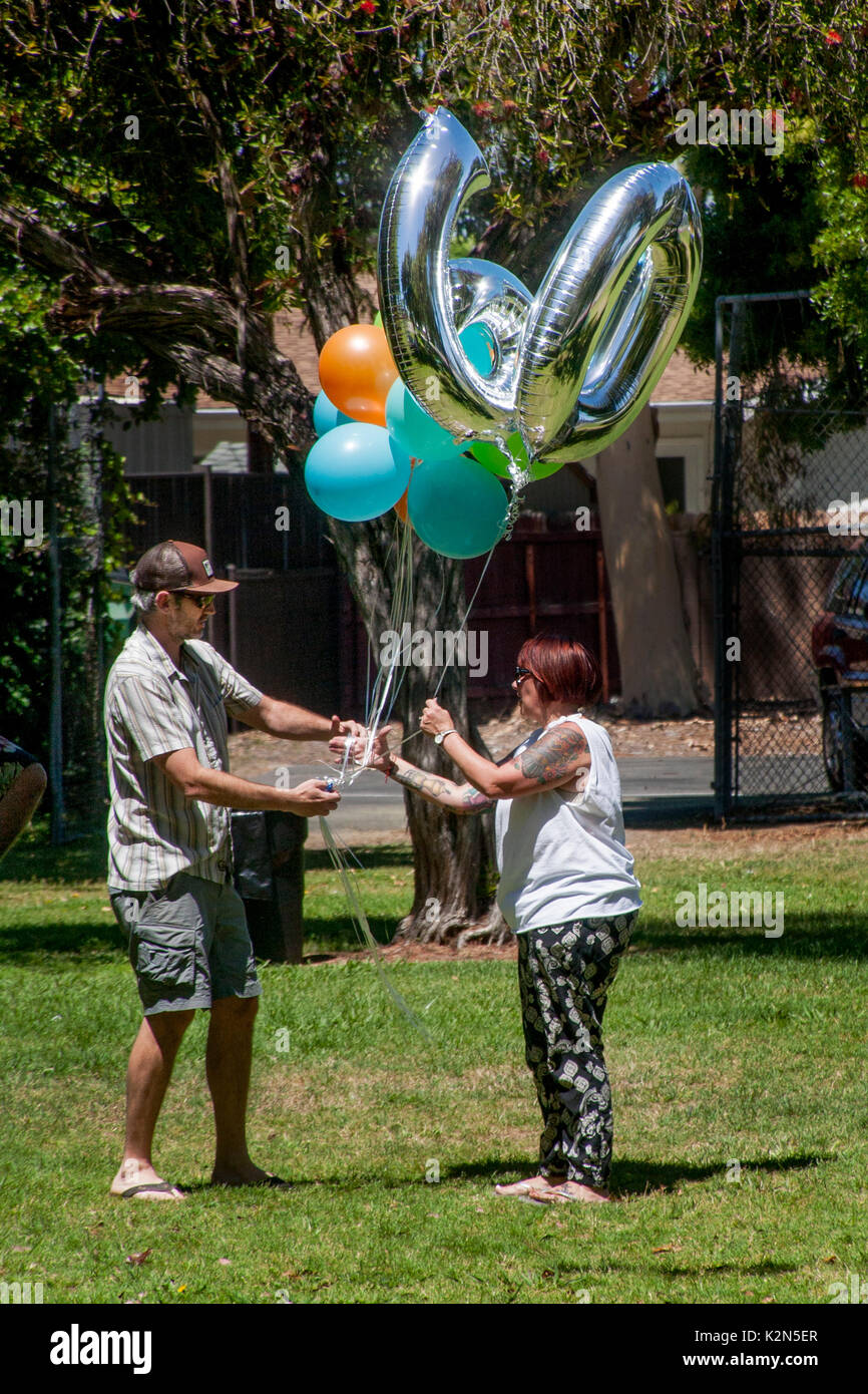 Two volunteers handle numbered balloons at the 60th anniversary of a ...