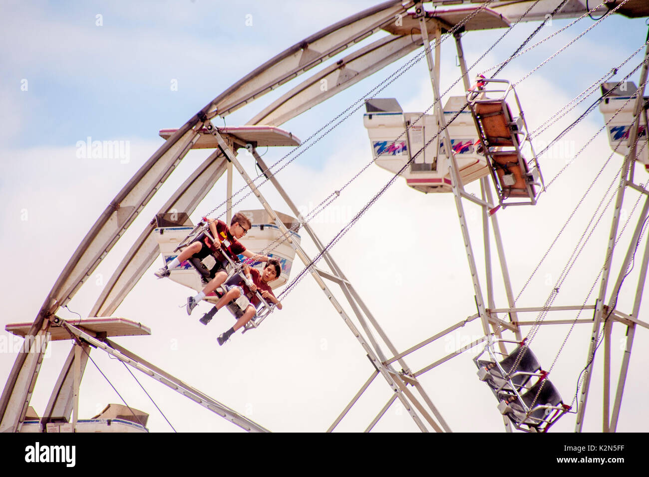 Boys on a "Vertigo" ride are juxtaposed with a Ferris wheel at a Costa ...