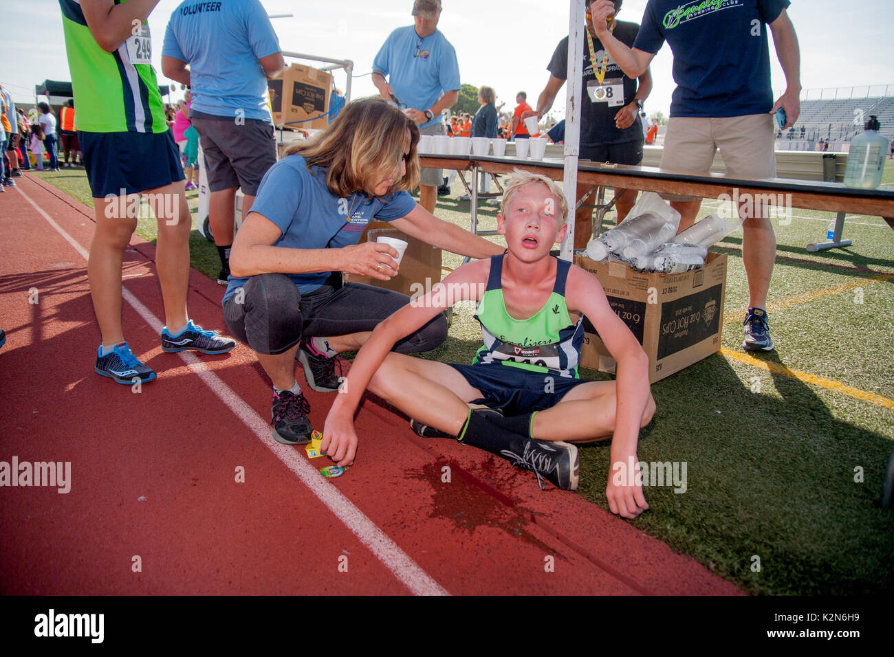 An exhausted young foot race participant gets support from a woman ...