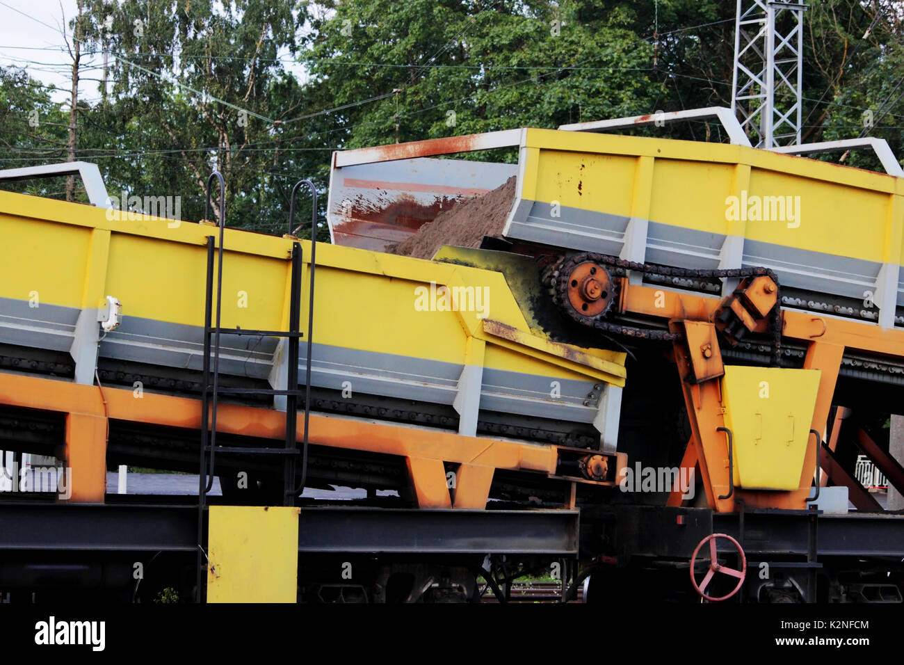 The railroad train platforms with gondola cars that contain a conveyor ...