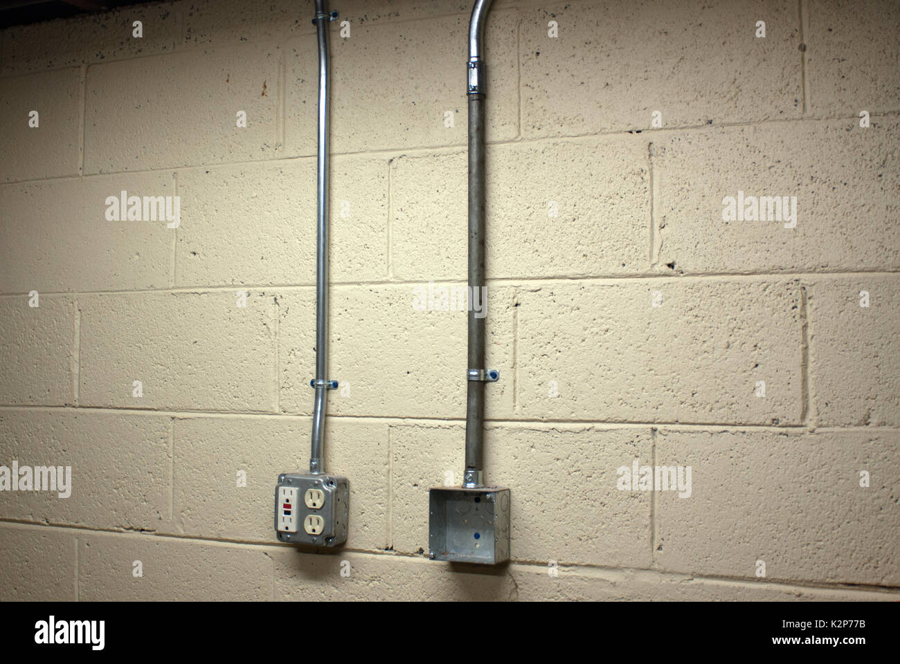 Electricity outlet boxes with conduit on painted cinderblock wall Stock ...
