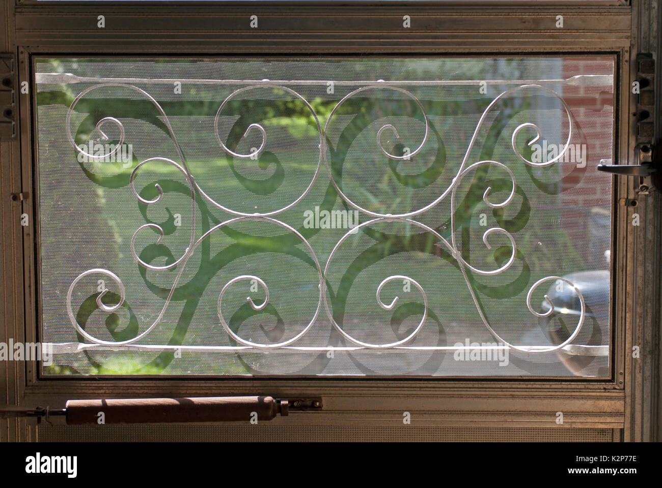 Mid-century decorative screen grate on a window in a door with grass ...