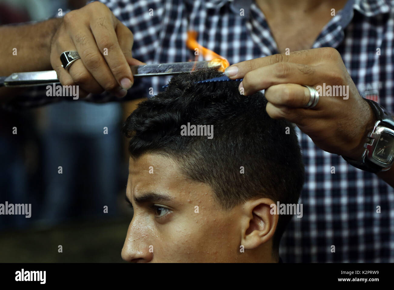 Gaza, Egypt. 01st Sep, 2017. A barber styles a client's hair with fire ...