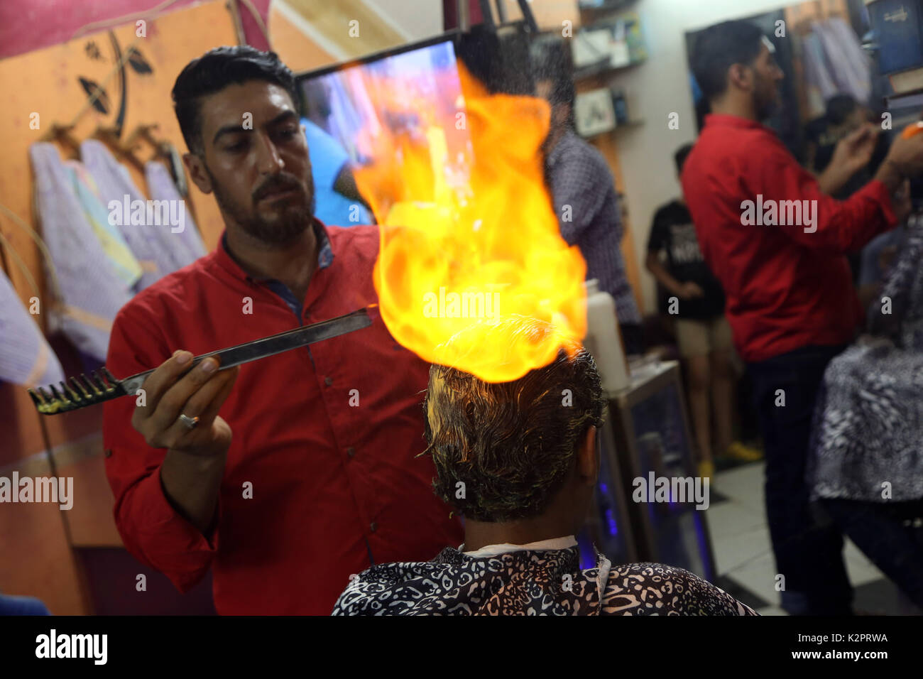Gaza, Egypt. 01st Sep, 2017. A barber styles a client's hair with fire ...