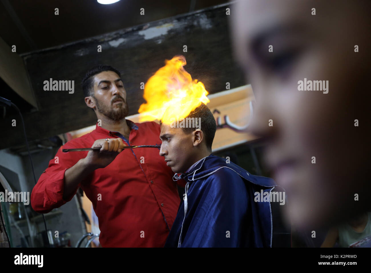 Gaza, Egypt. 01st Sep, 2017. A barber styles a client's hair with fire ...