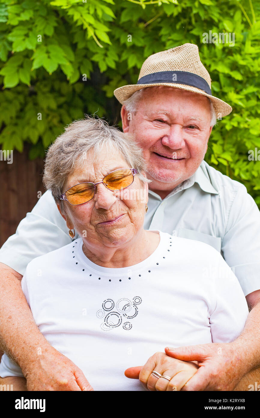 Cute elderly couple in love hugging and smiling outdoor in the green ...