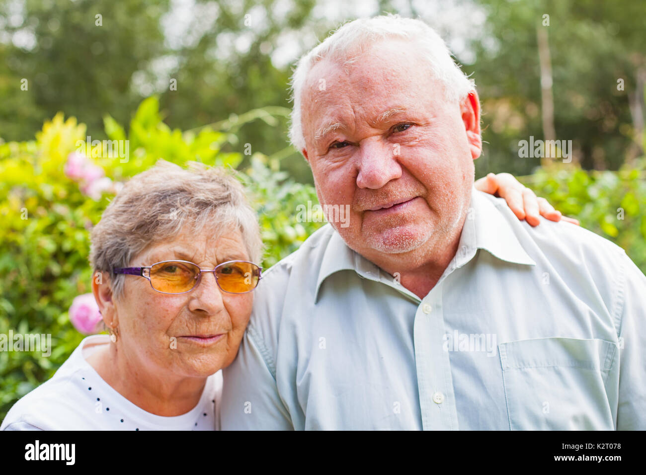 Portrait of a cute elderly couple hugging and smiling at the camera in ...