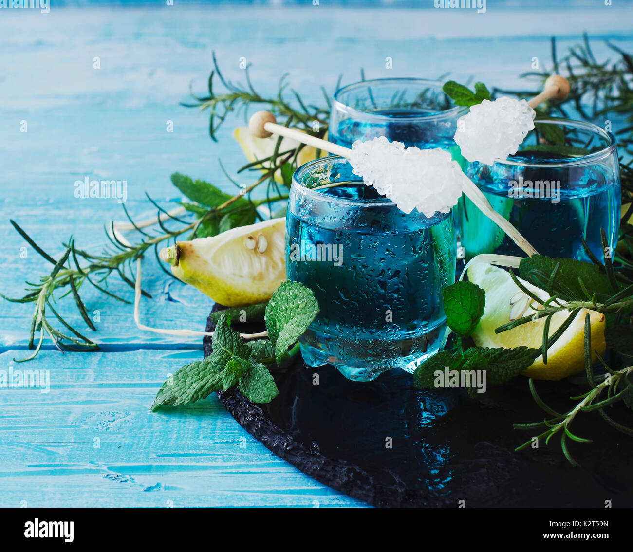 Blue curacao liqueur or sambuca with lemon on the wooden table ...