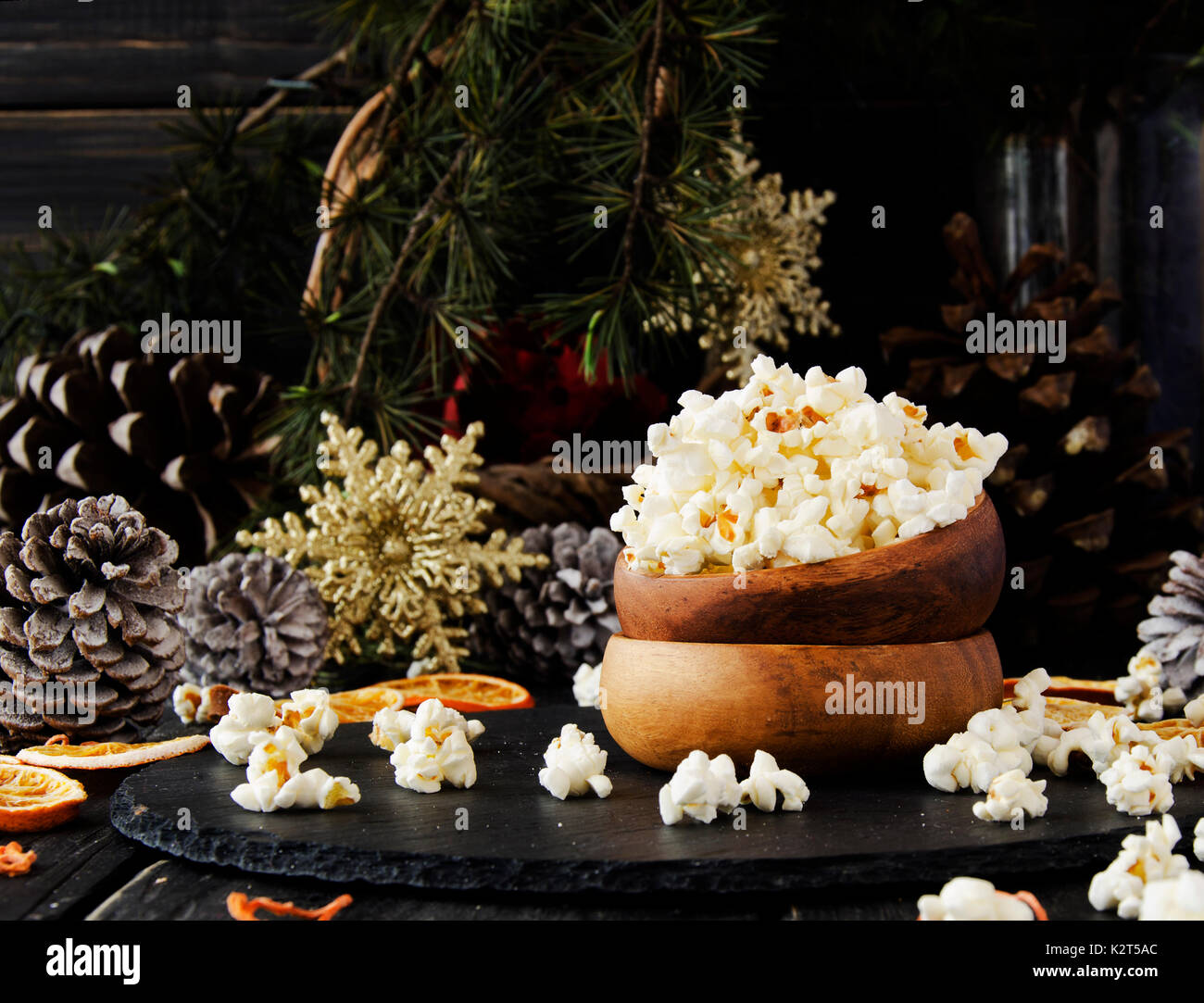 popcorn in a wooden plate on the background of Christmas trees and ...