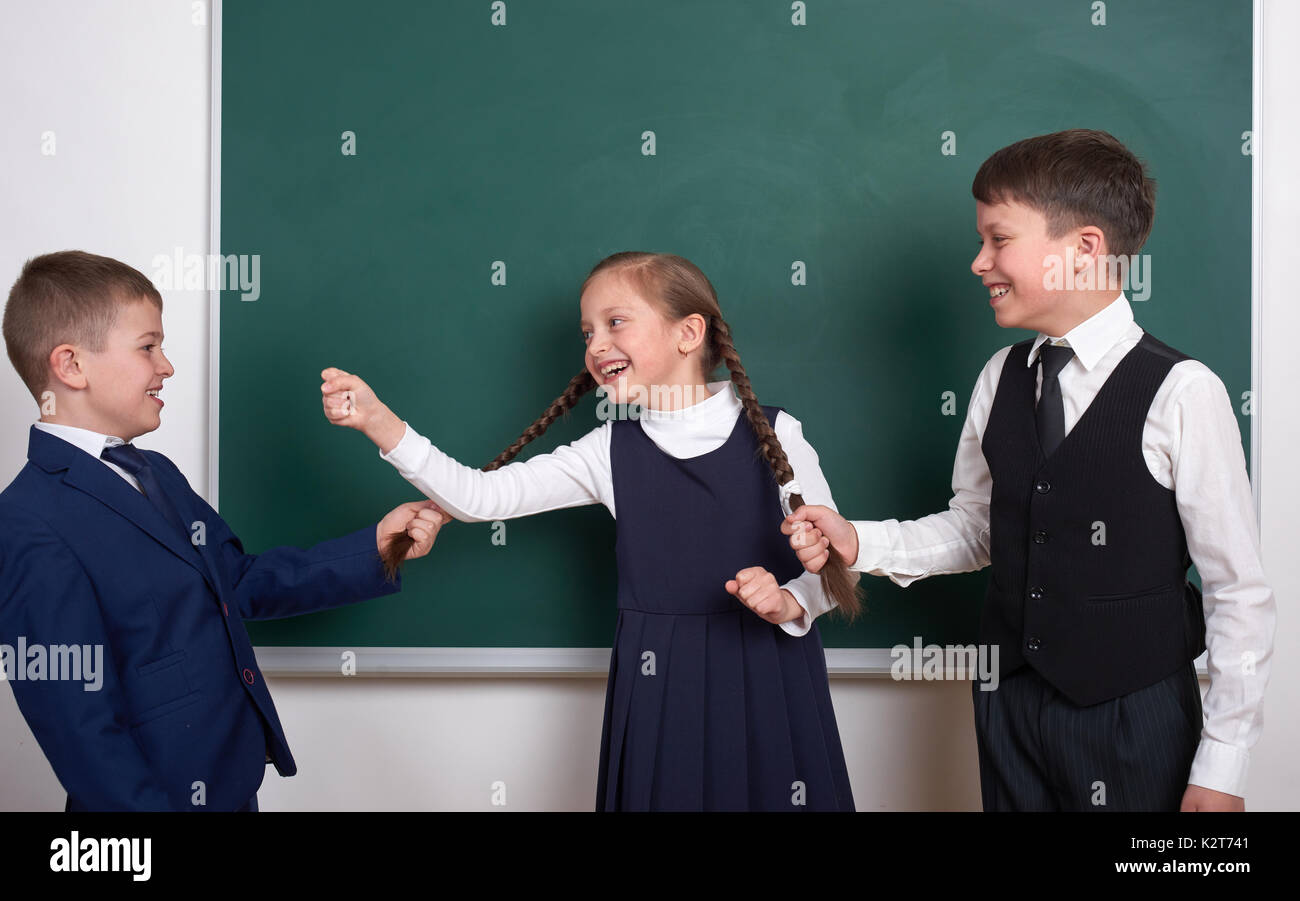 child play and having fun, boys pull the girl braids, near blank school ...