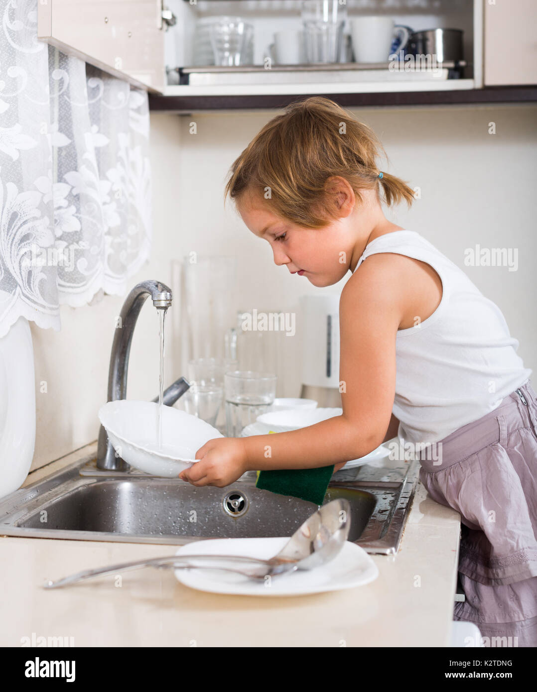 Cute little child washing dishes in kitchen at home Stock Photo - Alamy