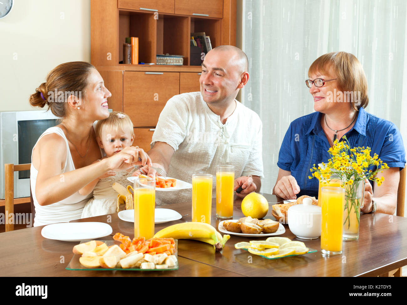 Happy smiling three generations family eating fresh friuts and ...