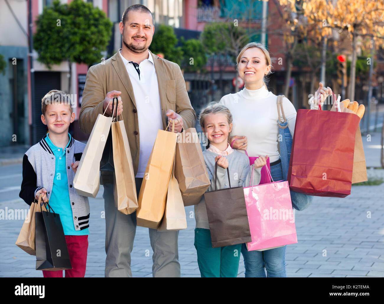 Young cheerful parents with two teenagers going for a shopping outdoors ...