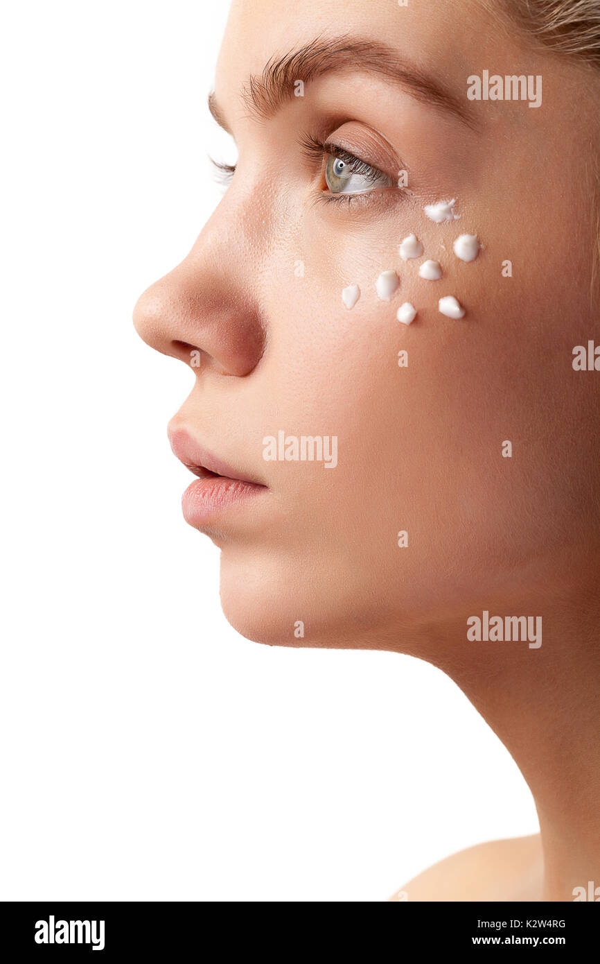Beautiful woman with cream face drops on her face. Studio photo. Beauty ...