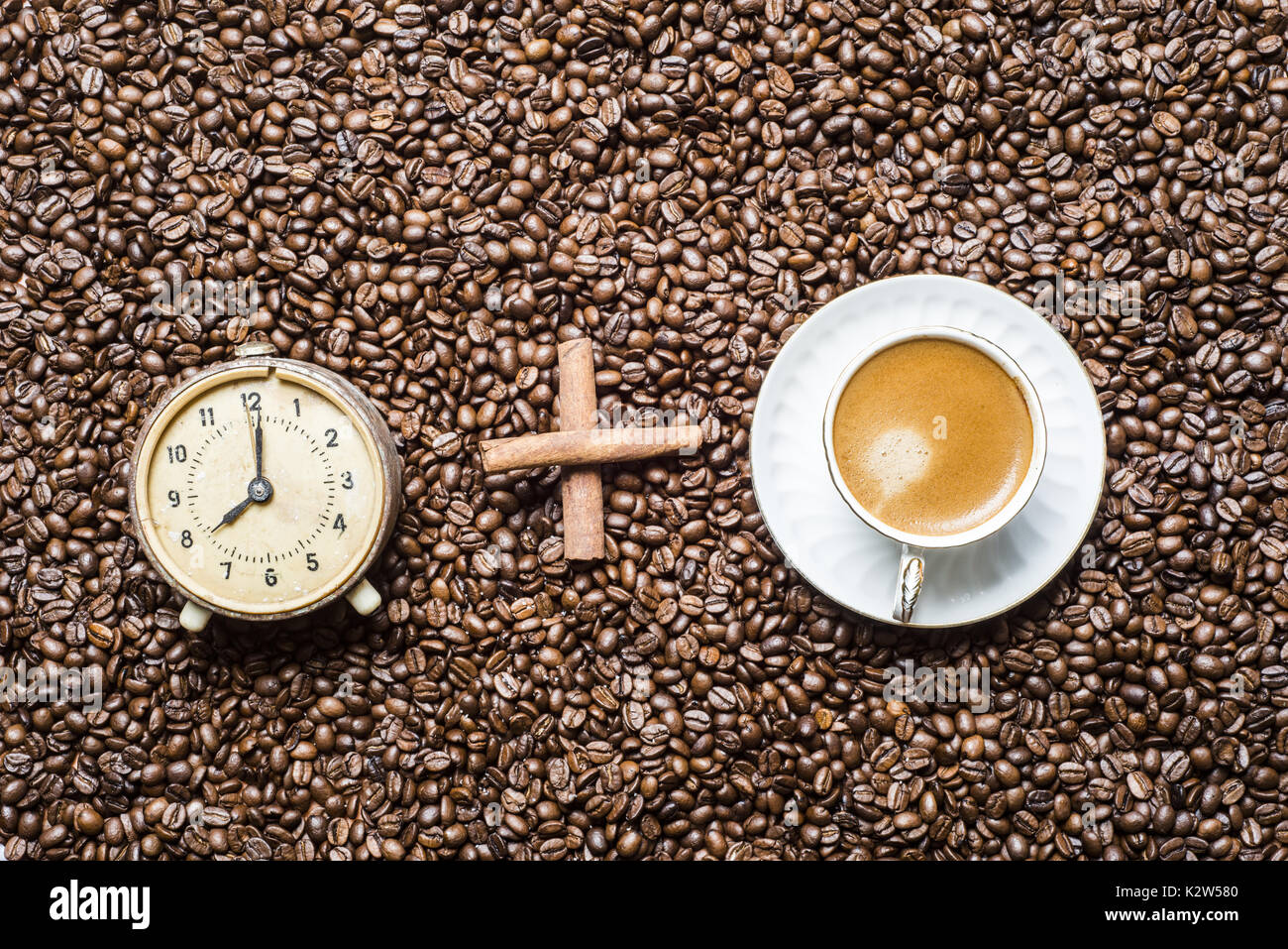 old alarm clock with cinnamon and a cup of coffee on the background of ...